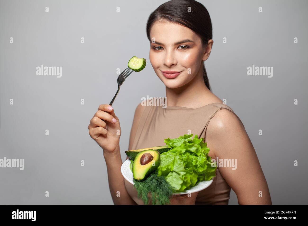 Young model healthy woman eating green vegetables avocado, cucumber and ...