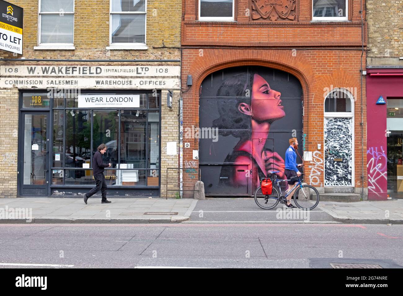 People walking past mural painting artwork of pink woman by artist ...