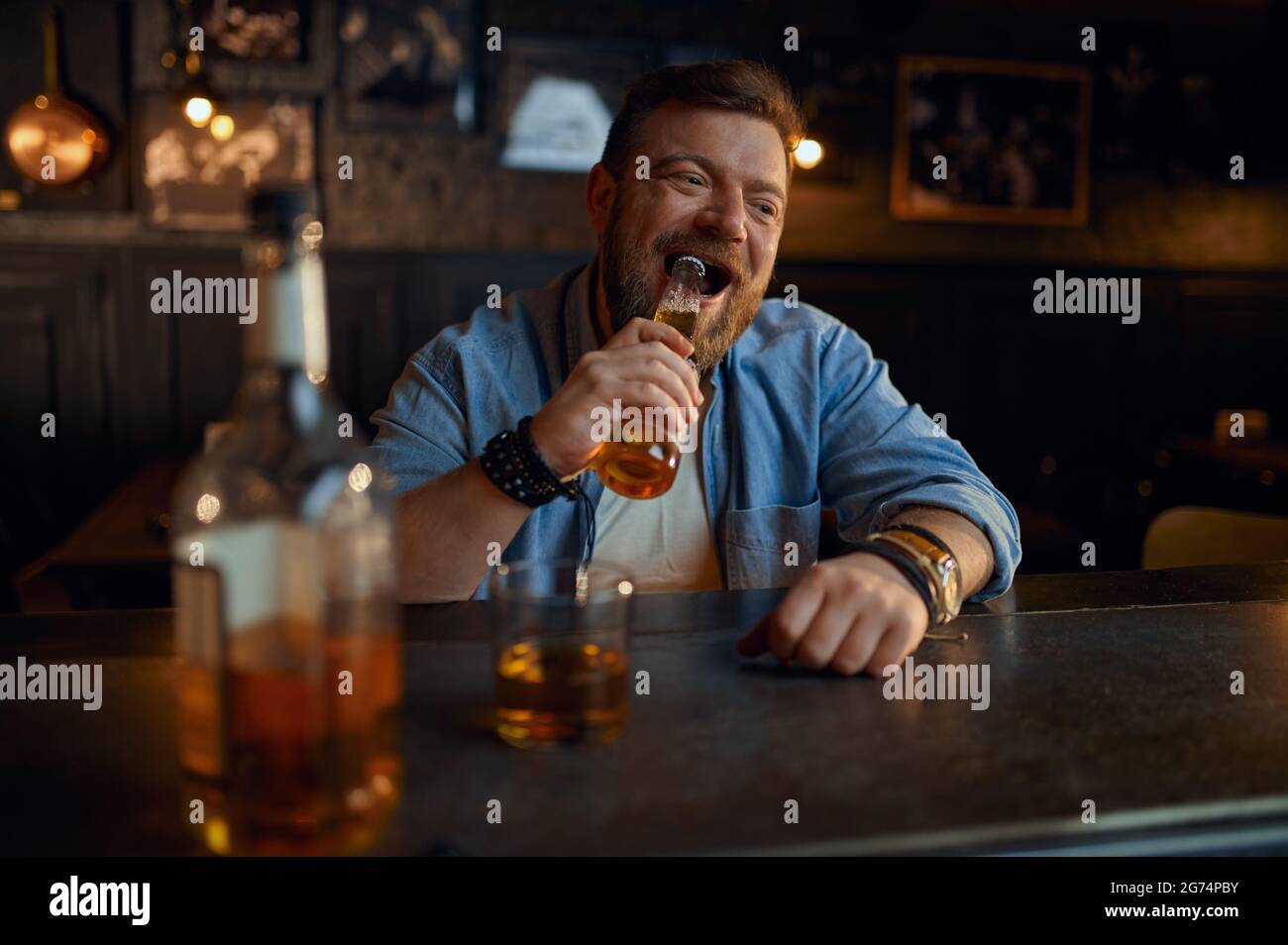 Man opens bottle of beer with his teeth in bar Stock Photo - Alamy
