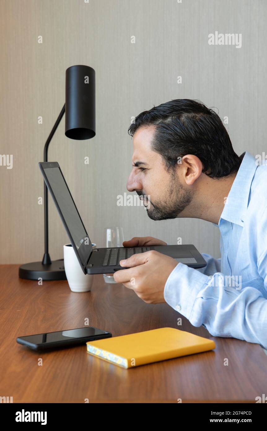 Man with a poor eyesight working inhis laptop, struggling to see Stock ...