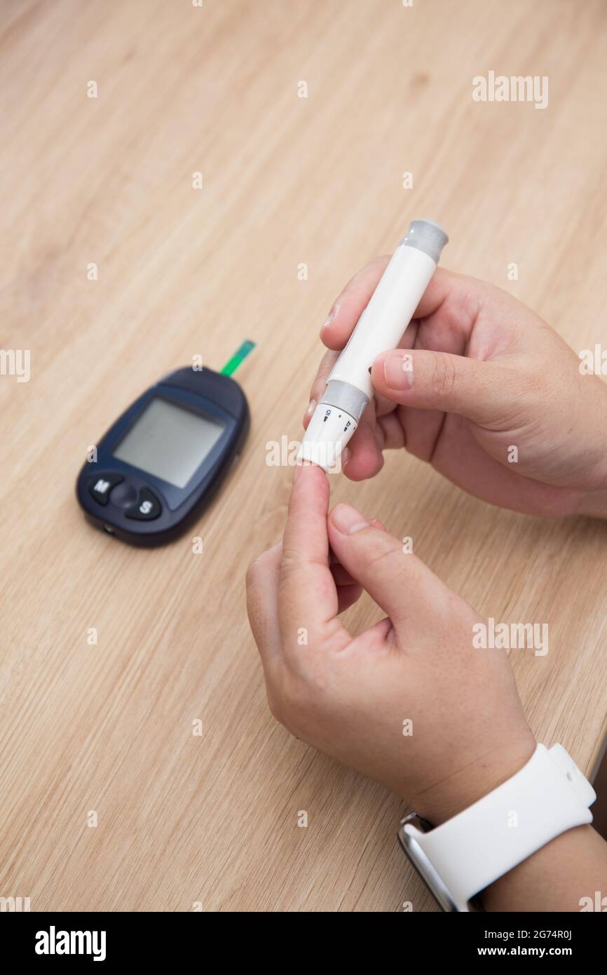 A vertical shot of female hands with glucometer testing blood sugar ...