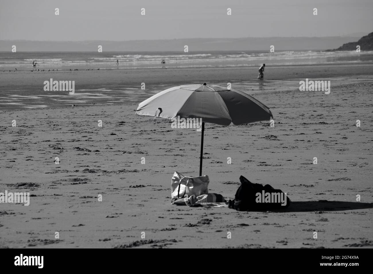 Surfers of all ages carry surfboards to the water's edge of Llangennith ...