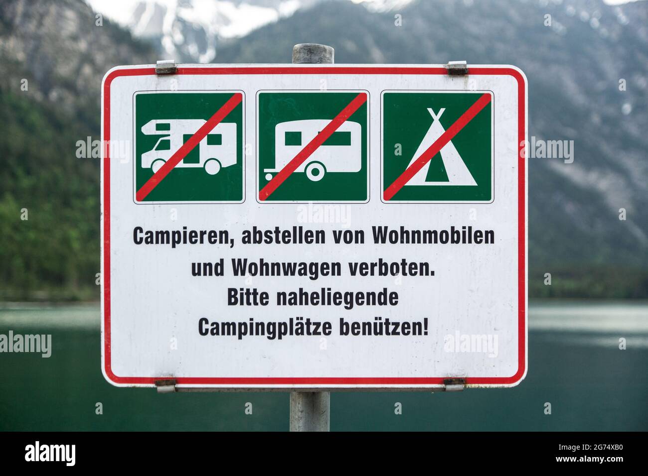a sign with crossed vehicle icons and tent icons and german text ...