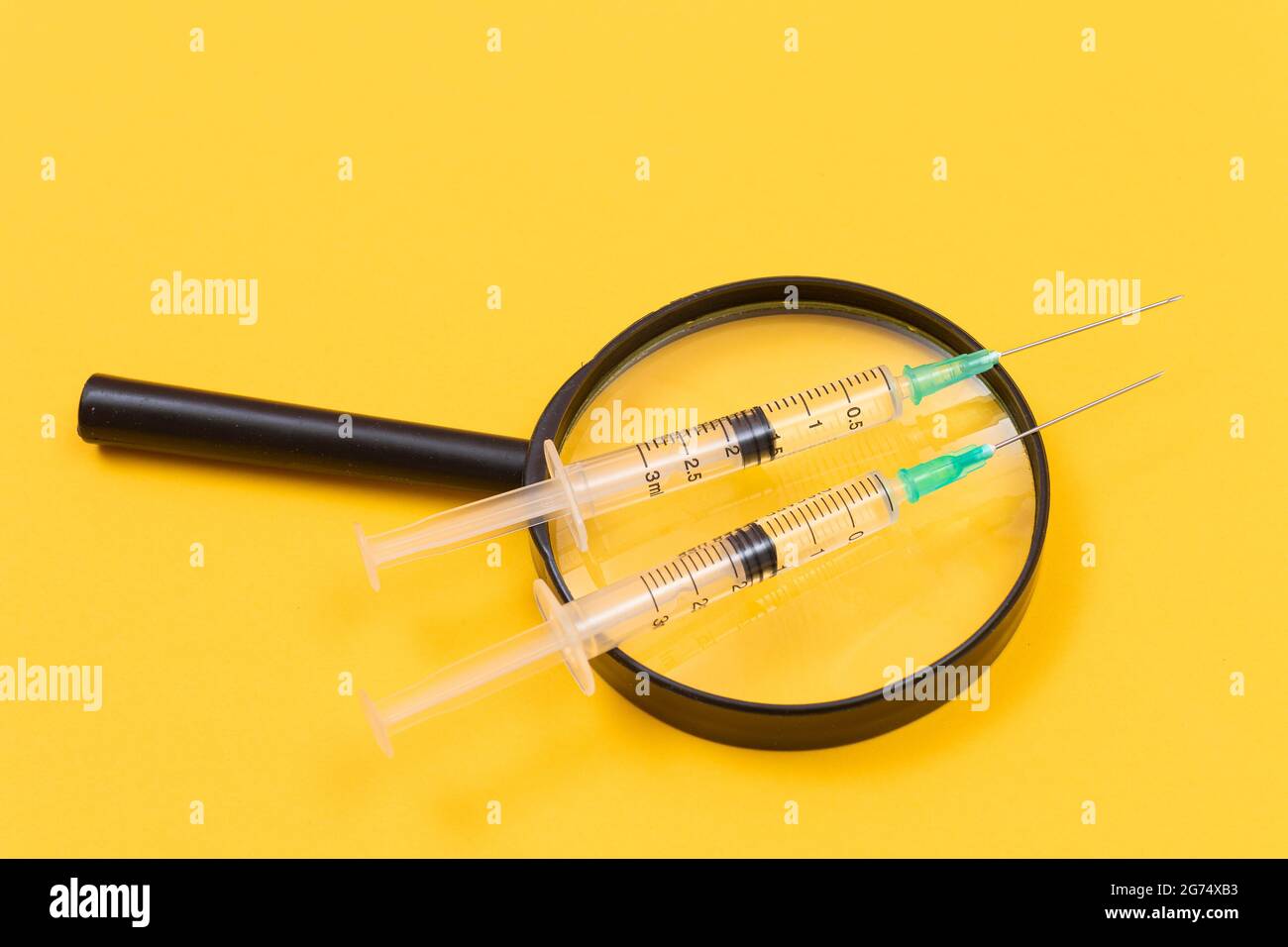 A Magnifier with Medical Syringe Lying on Yellow Table - Vaccination ...