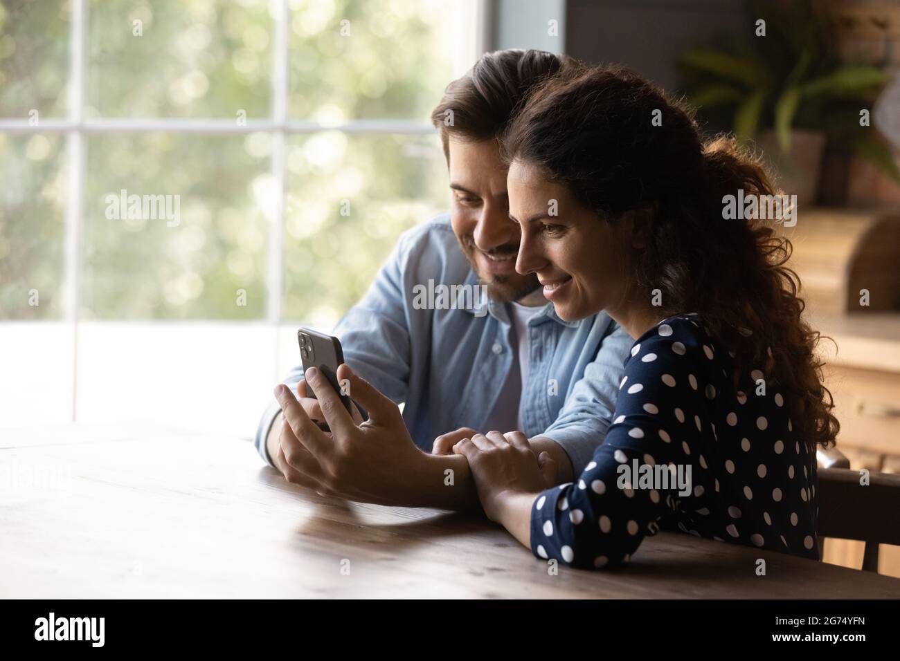 Happy young couple sharing mobile phone, watching content Stock Photo ...