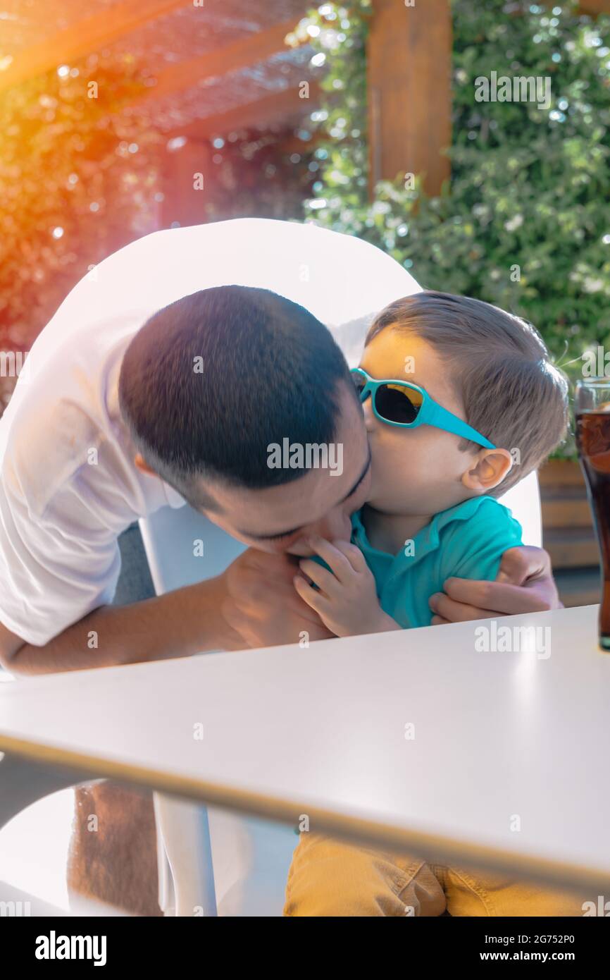 boy in sunglasses showing affection and giving a kiss to a teenage boy ...