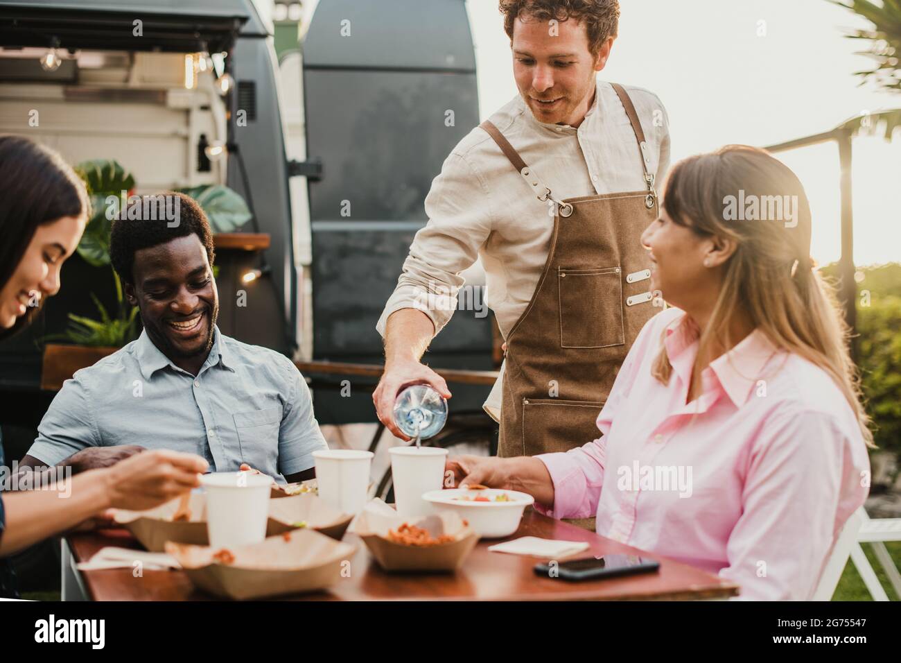 Happy people having fun eating at food truck restaurant outdoor in the ...