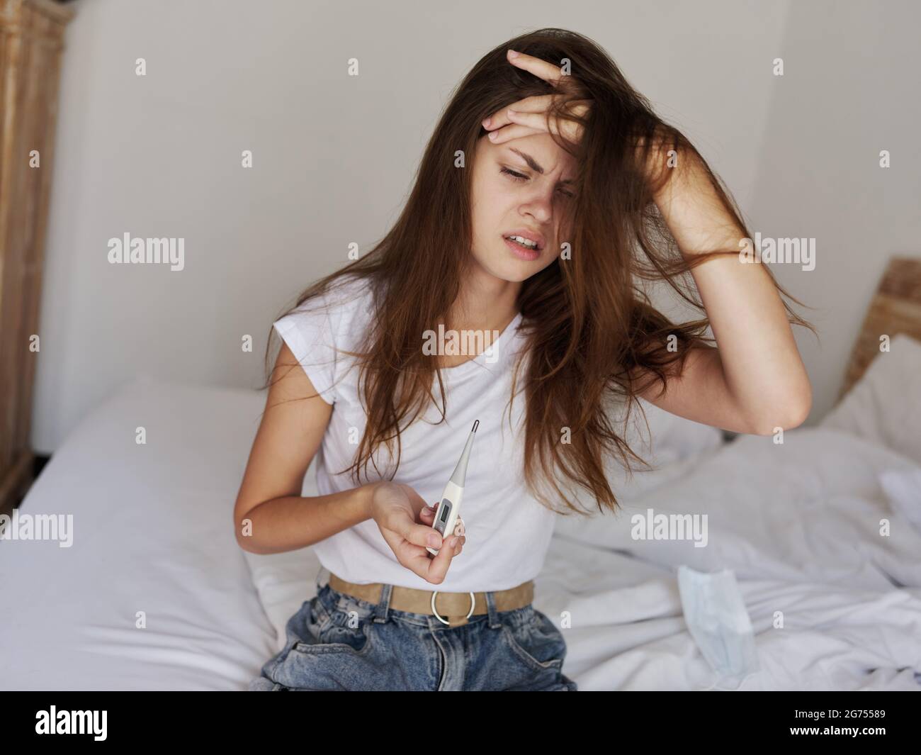 woman holding forehead thermometer in hands upset fever Stock Photo - Alamy