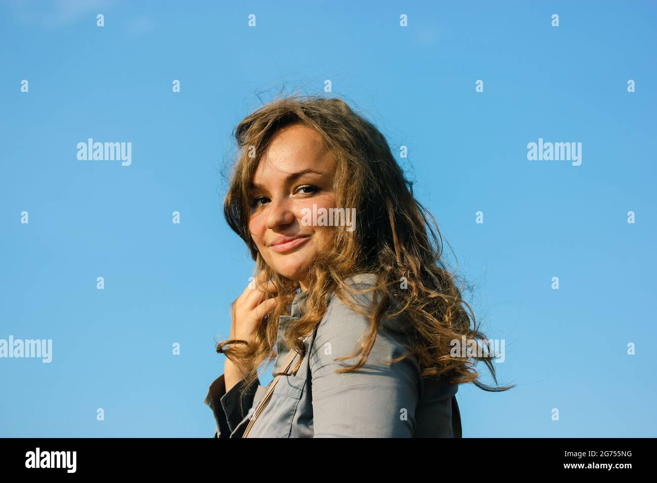 A beautiful swarthy woman with brown curly hair waving in a wind on a ...