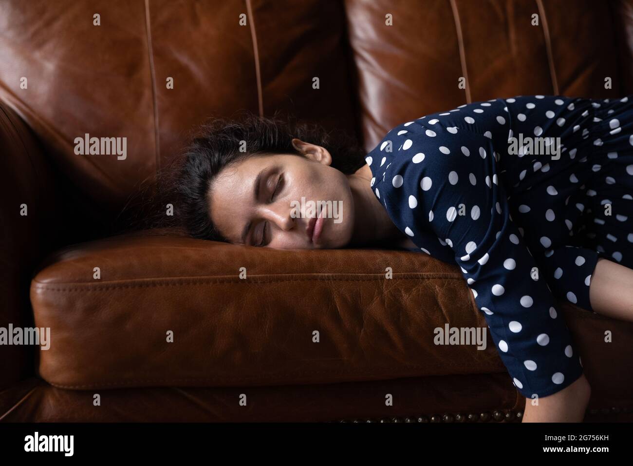 Tired peaceful Latin woman with closed eyes lying on sofa Stock Photo ...