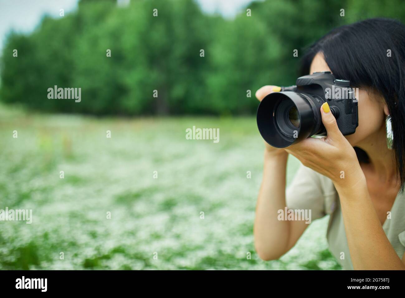 Portrait of Female photographer take photo outdoors on flower field ...