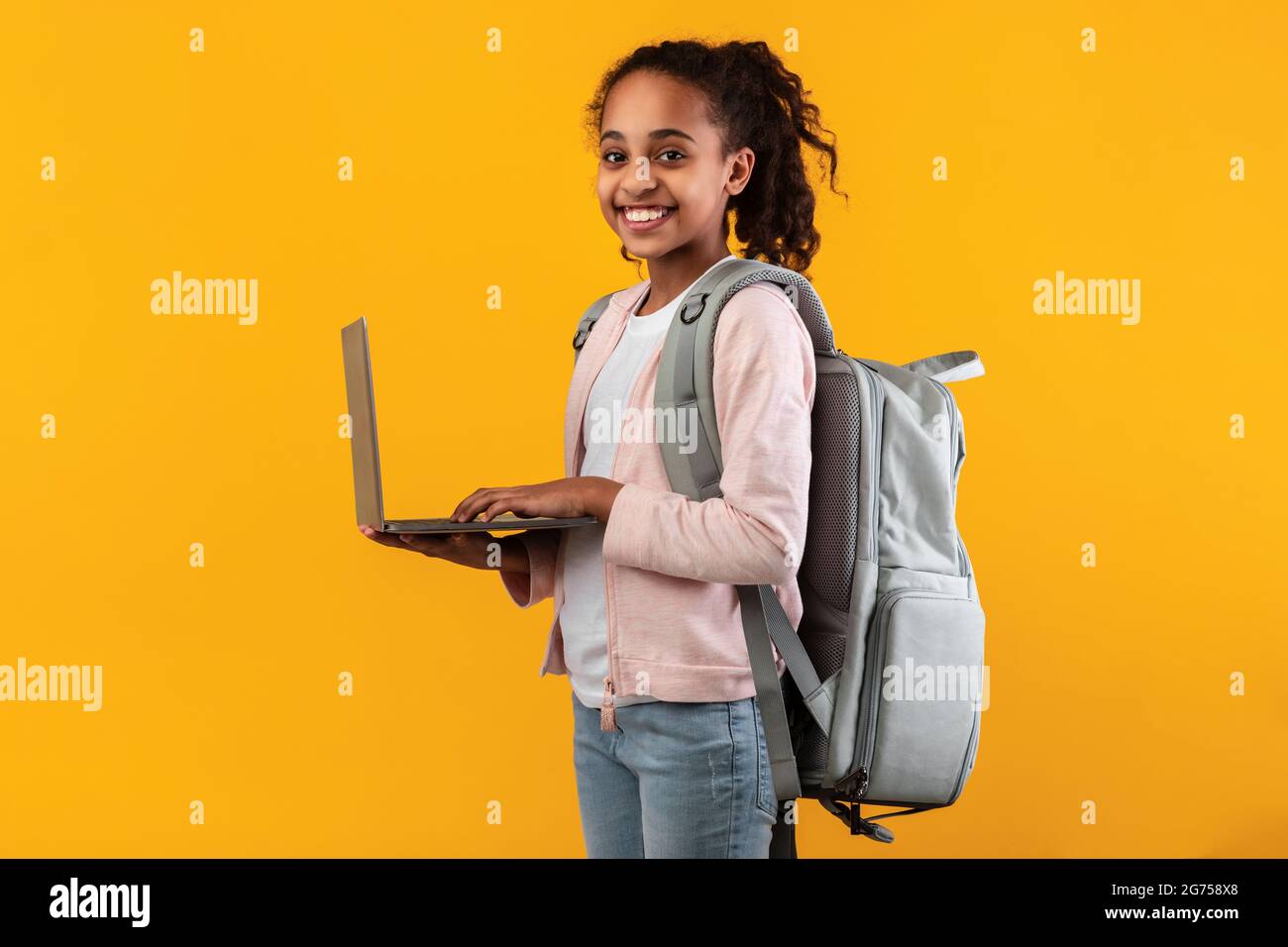 Black girl standing with personal computer at yellow studio Stock Photo ...