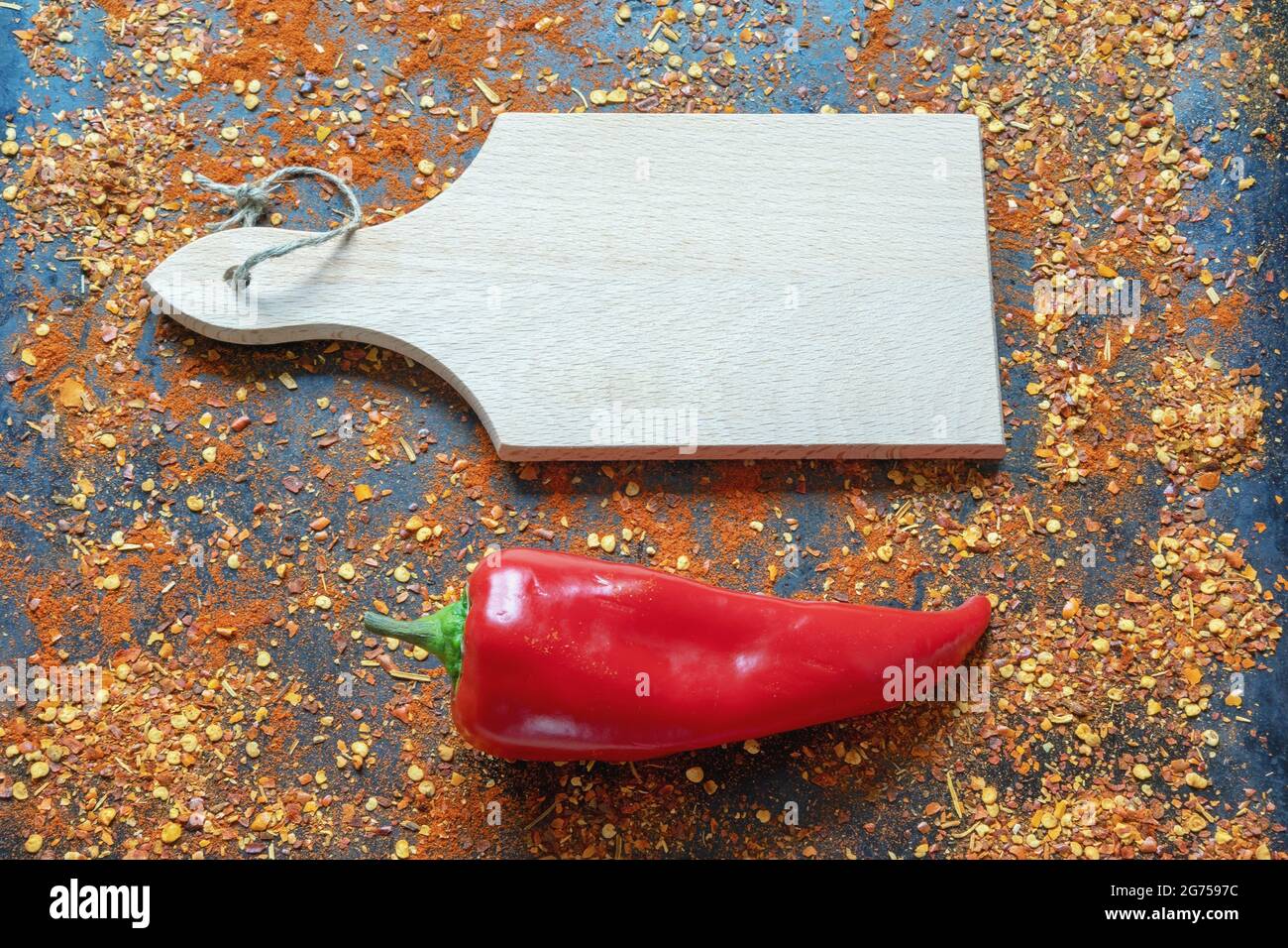 Bright red bell pepper and cutting board with crushed hot paprika ...