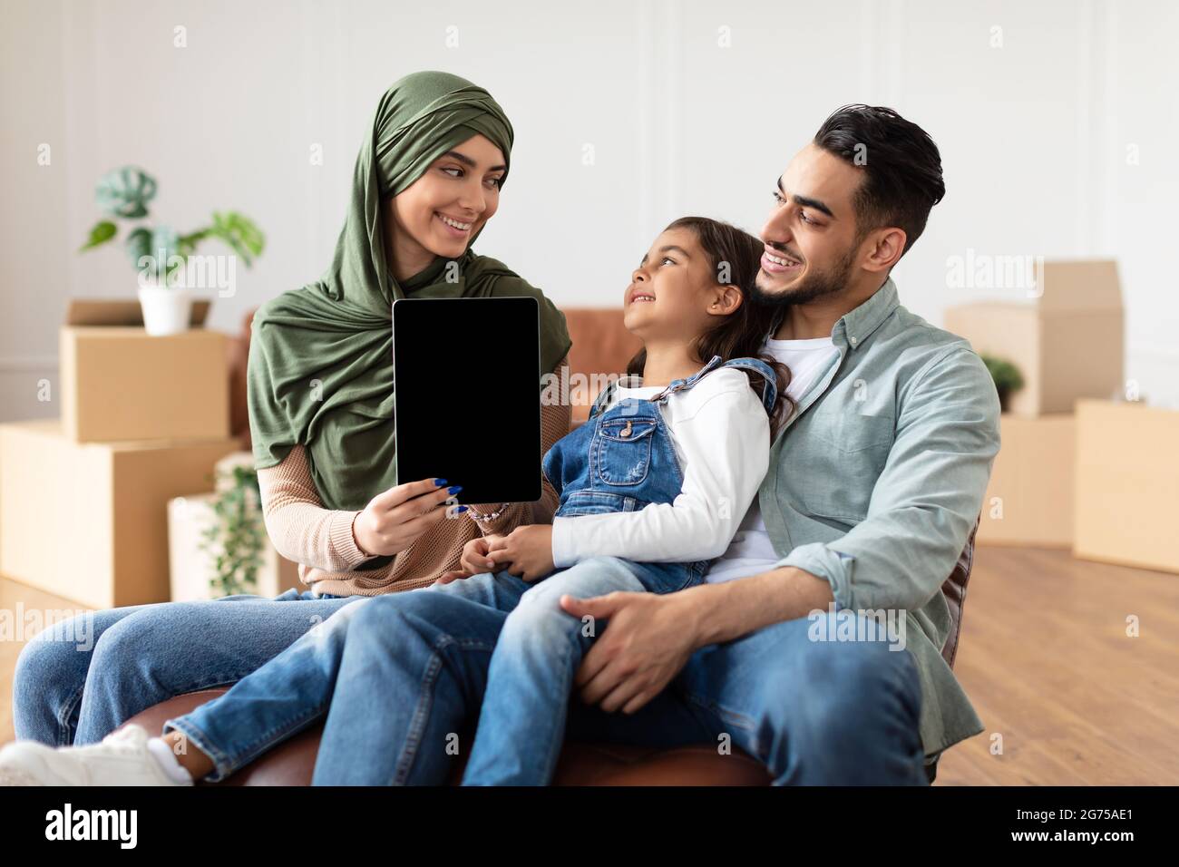 Happy muslim family doing repair woman showing tablet Stock Photo - Alamy
