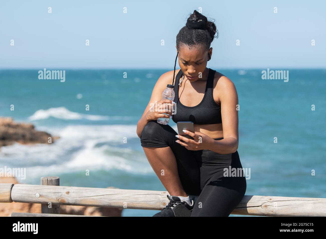 Afro american woman checking her phone on a break after exercising ...