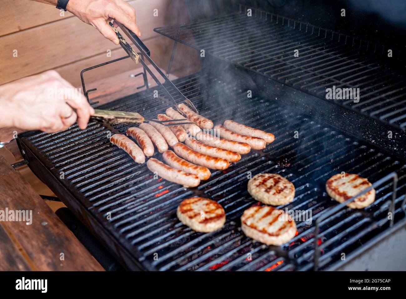 Grilling at summer weekend. Fresh meat preparing on grill.Man hand at a ...