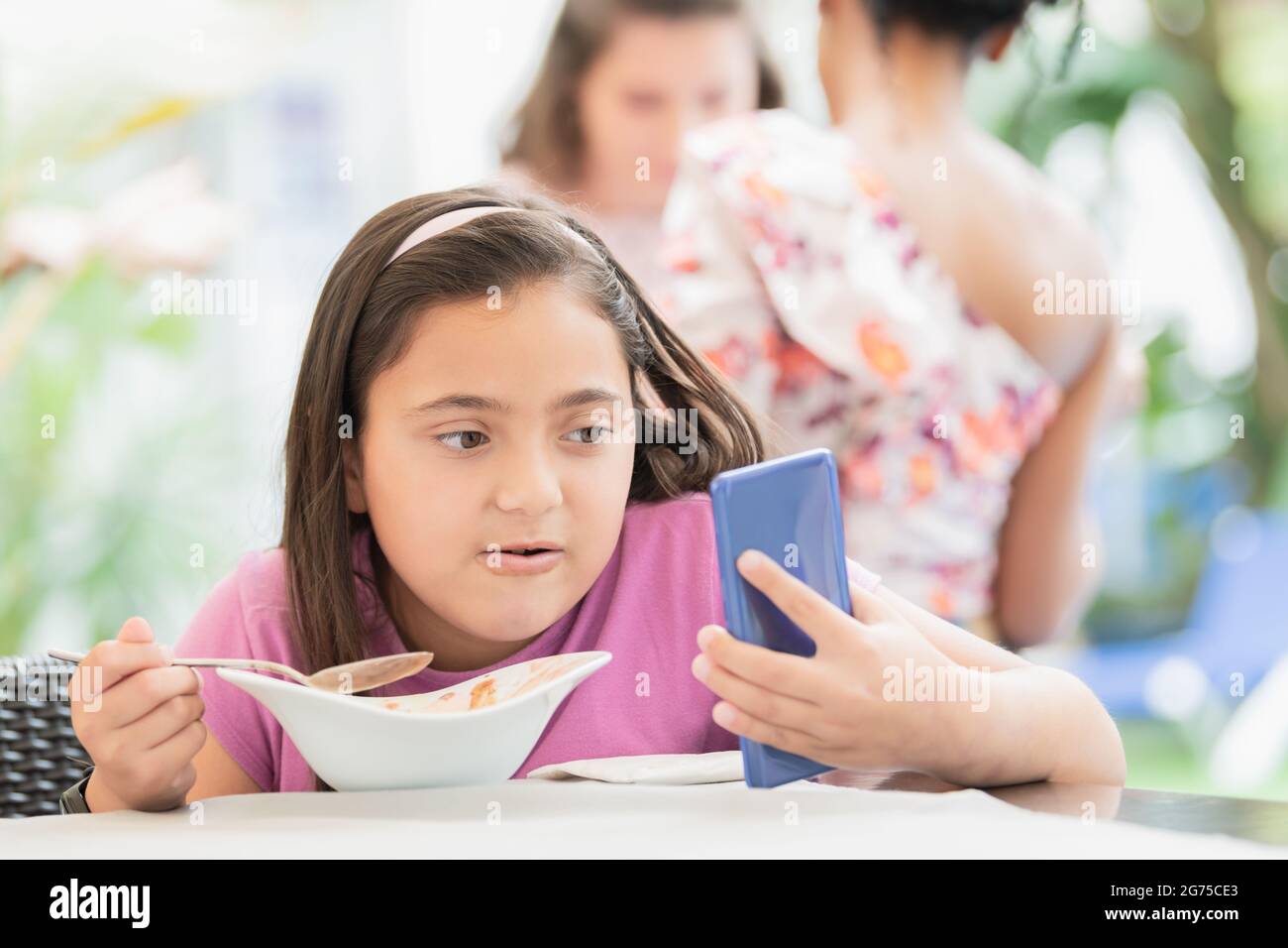Cute little girl checking her phone and eating ice cream Stock Photo ...