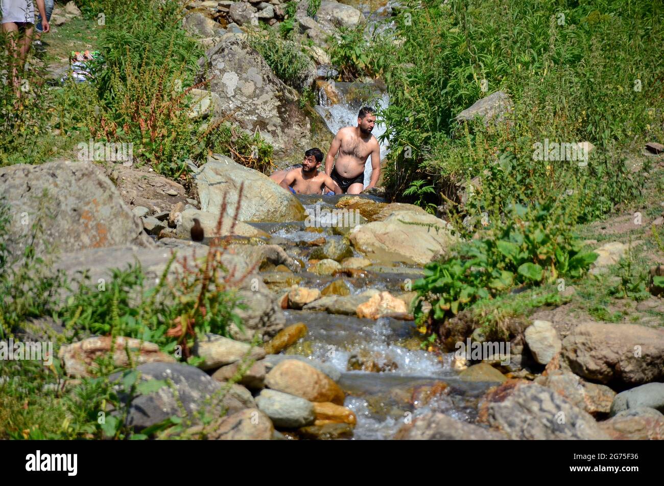 Kashmiri men cool off in a stream during a hot summer day on the ...
