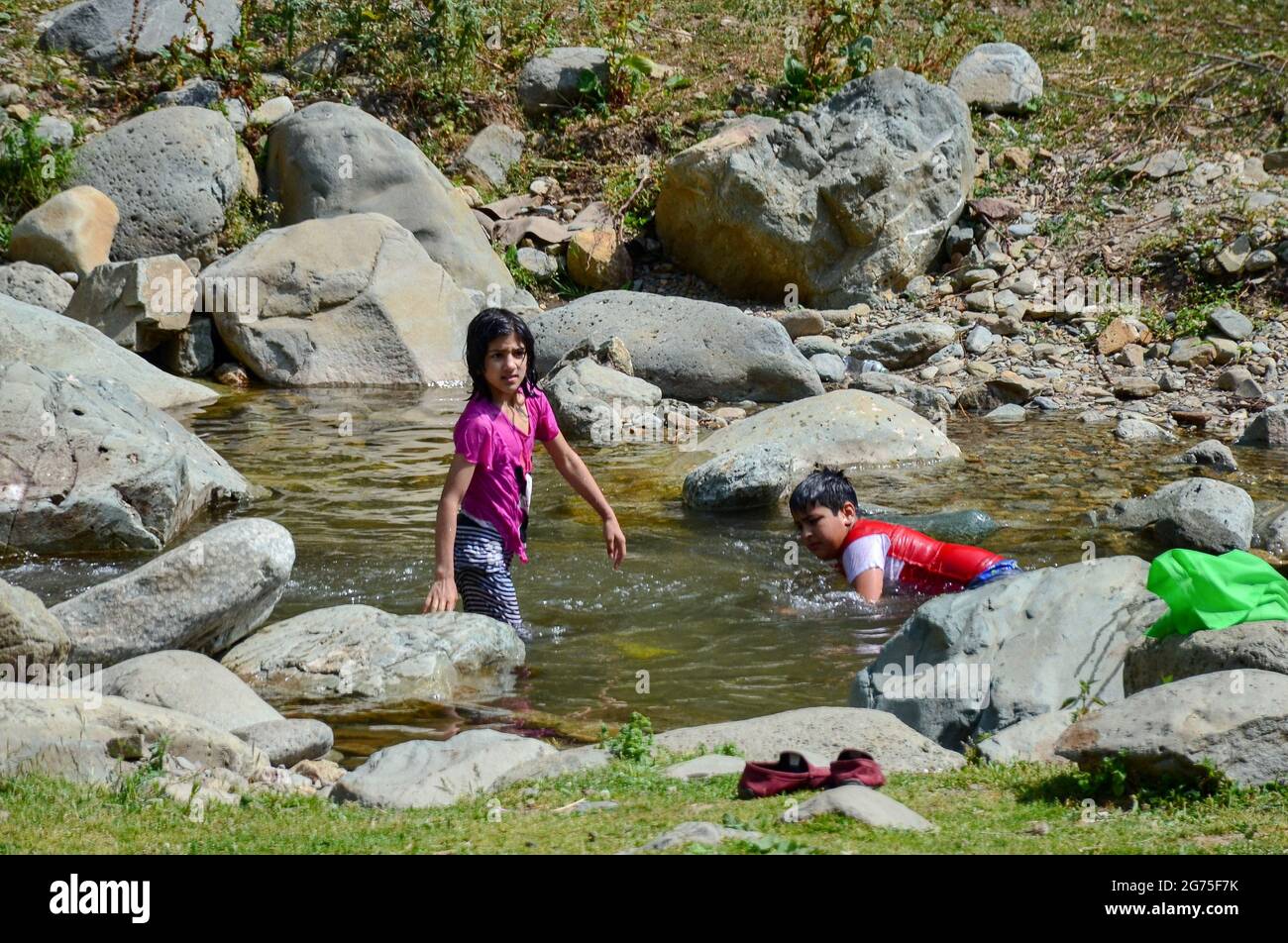 Kashmiri children cool off in a stream during a hot summer day on the ...