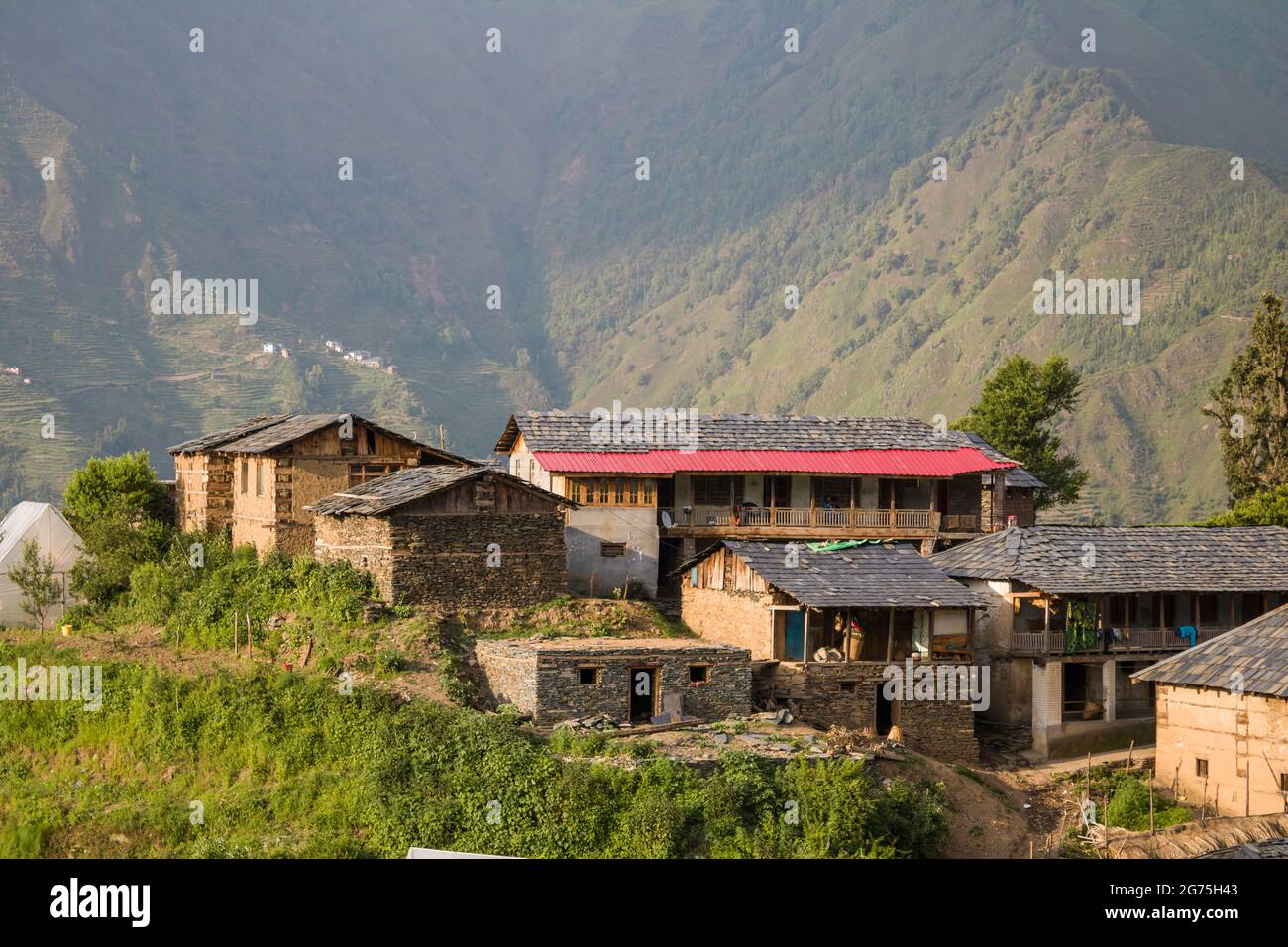 An aerial view of a small poor village on the hill surrounded by green ...