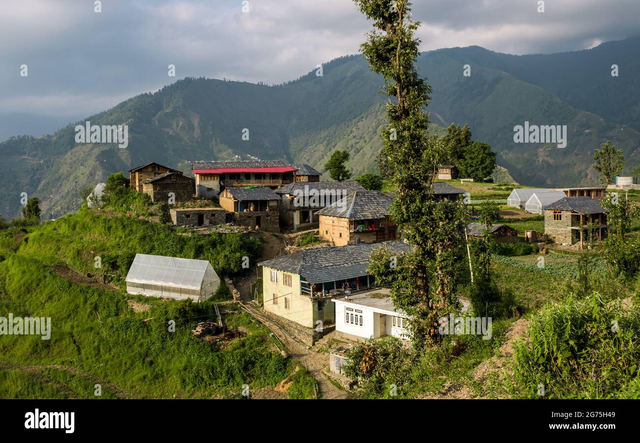 An aerial view of a small poor village on the hill surrounded by green ...