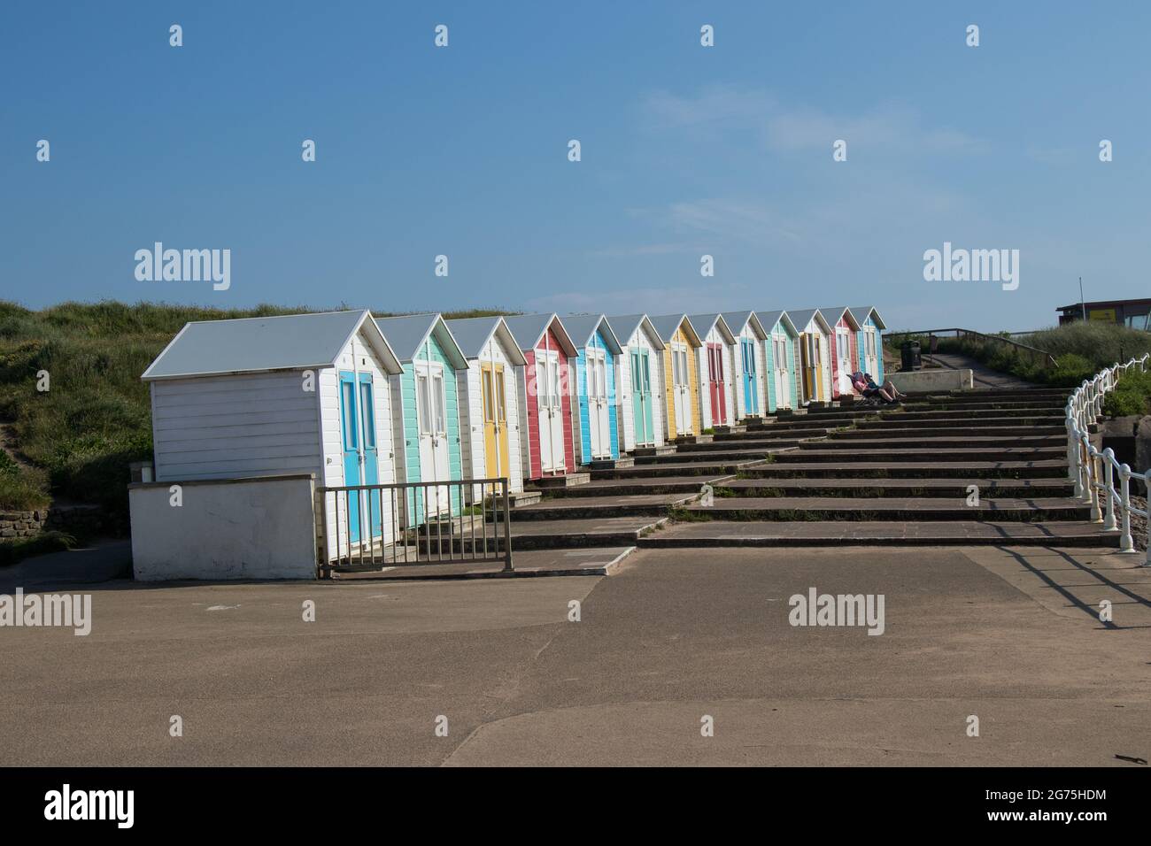 White beach huts with different colour doors next to steps at Crooklets ...