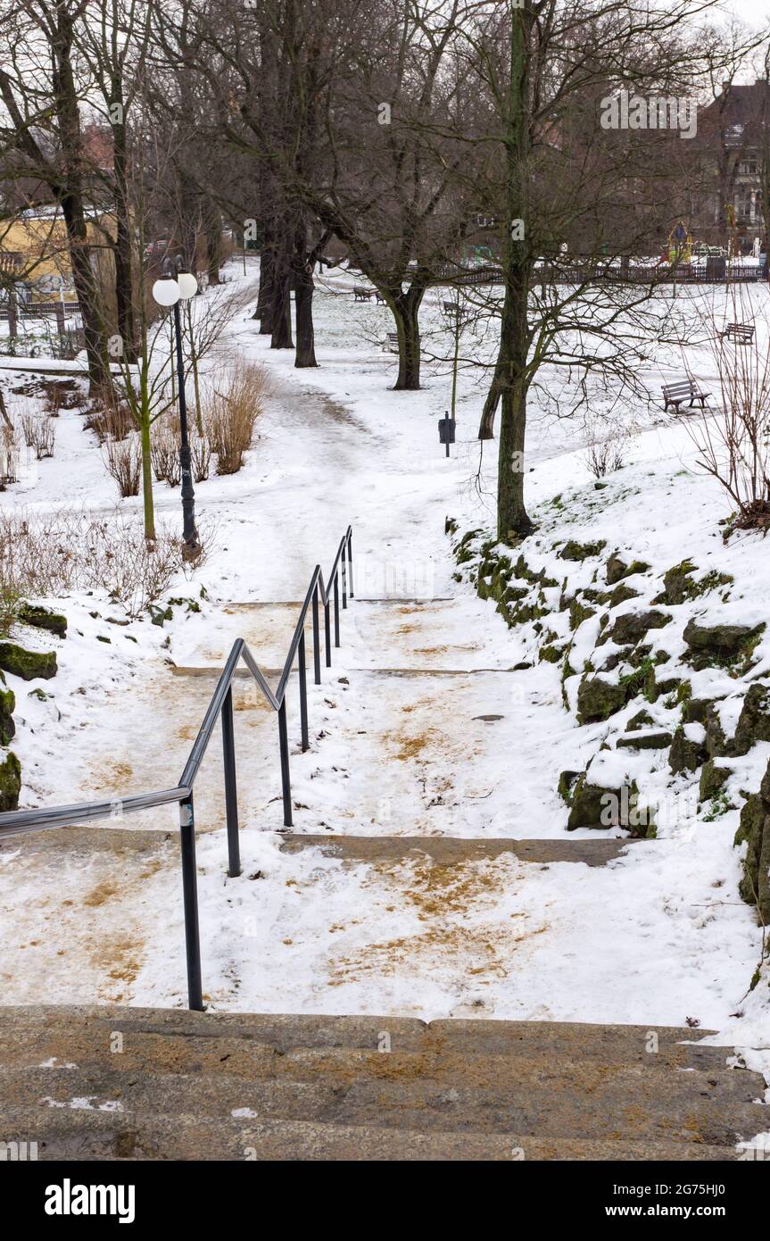 A vertical shot of stairs covered with snow leading to a park in the ...