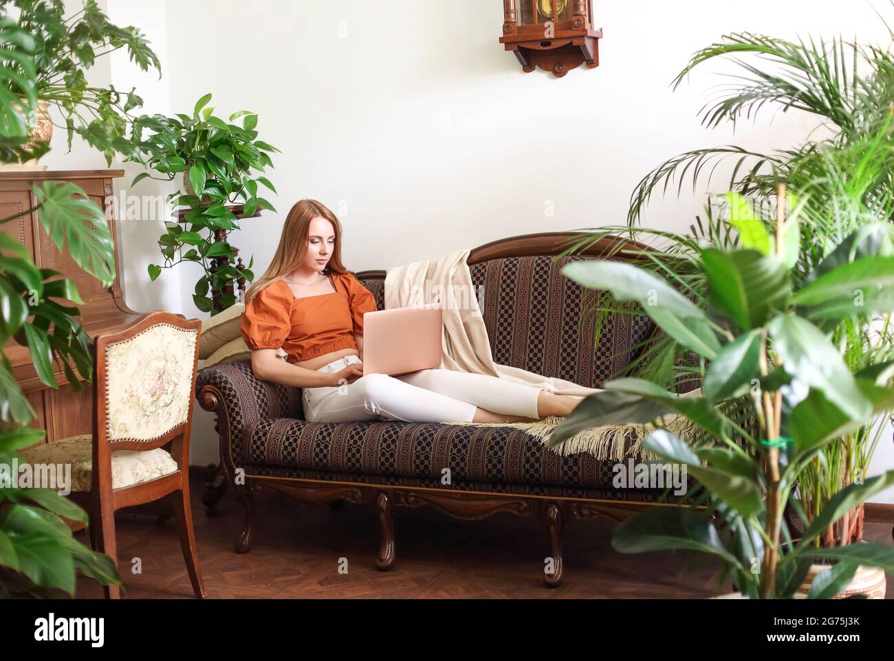 Barefoot female using netbook while relaxing on elegant couch amidst ...