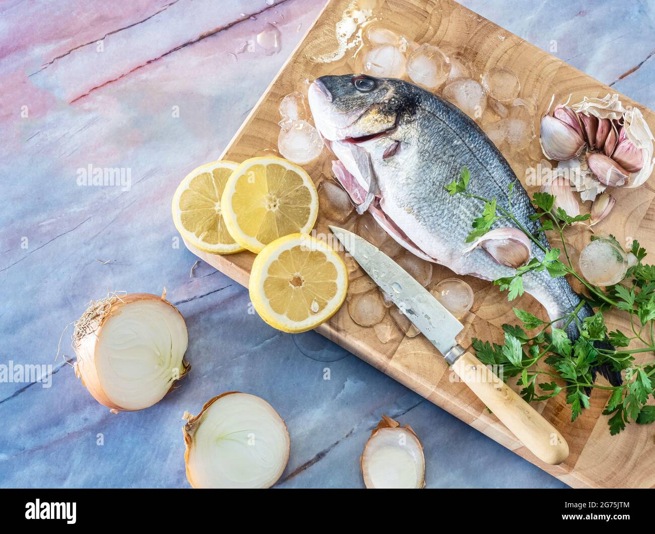 Fresh fish Dorado. Raw sea bream with parsley, onion, garlic and lemon ...