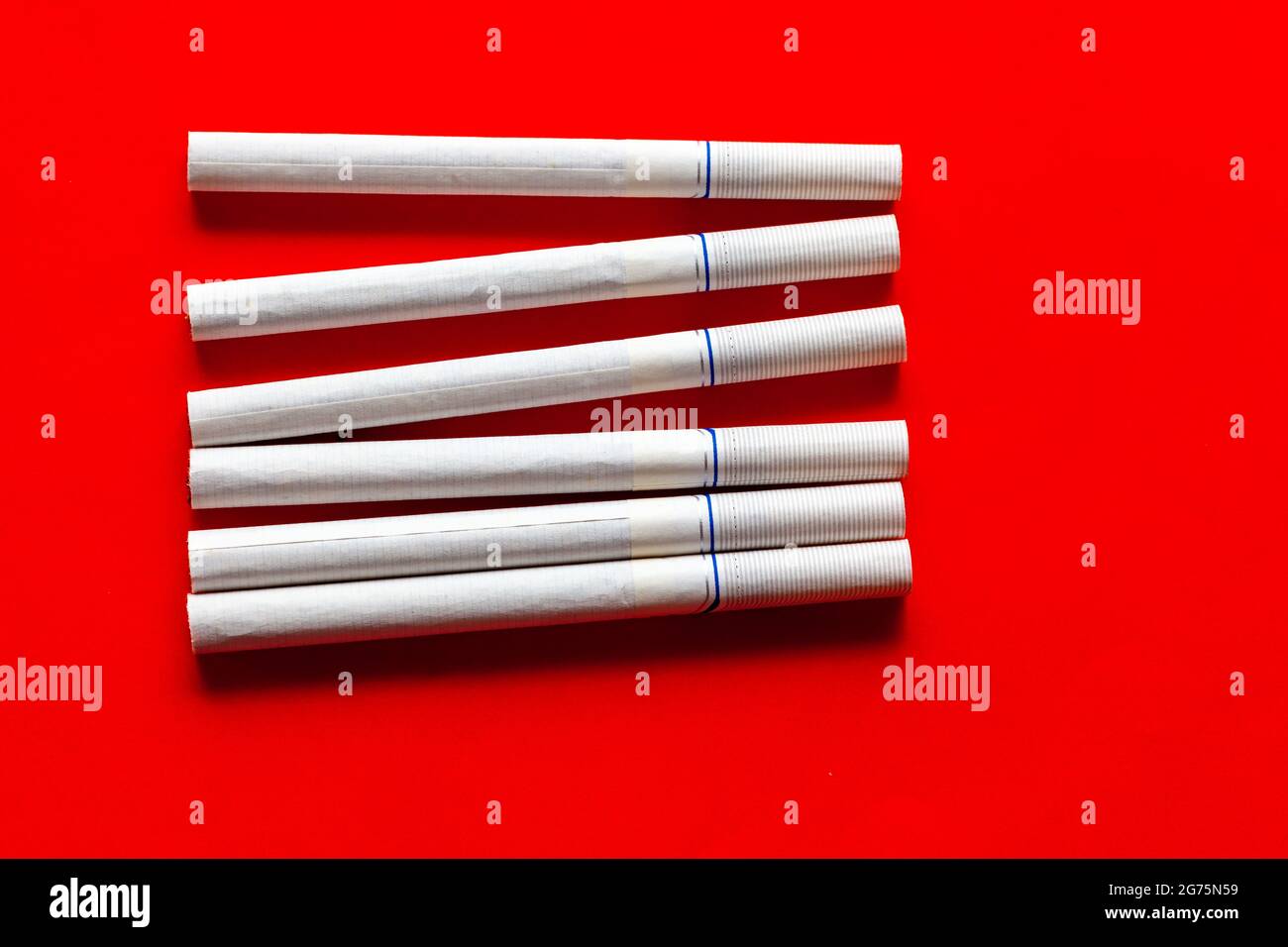 White cigarettes at red background . Bad habit . Nicotine in cigarettes ...
