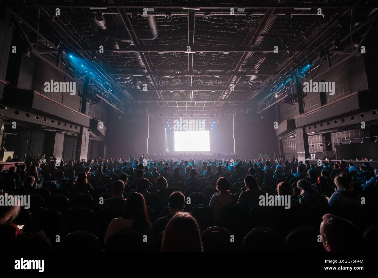 Audience sitting in front of stage with screen Stock Photo - Alamy