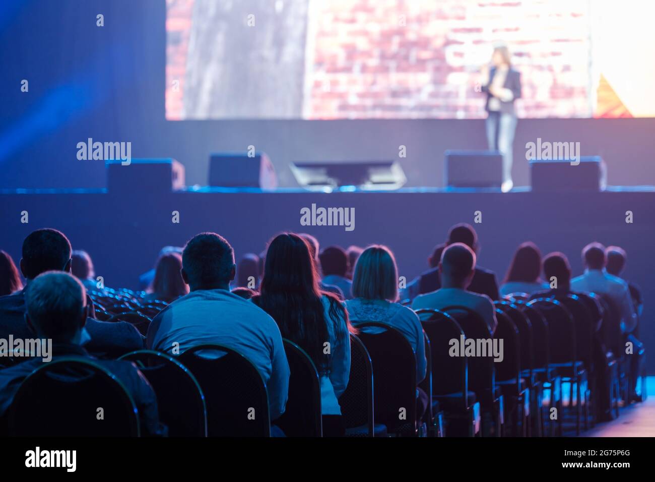Audience listening to speaker in neon light Stock Photo - Alamy