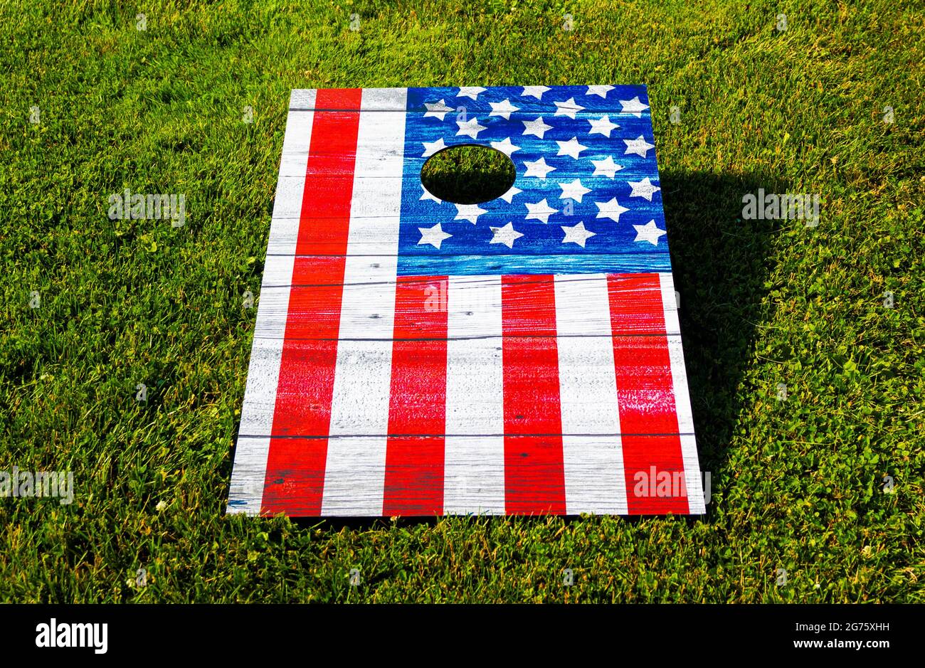 Red white and blue cornhole game looks like an American Flag on a green ...