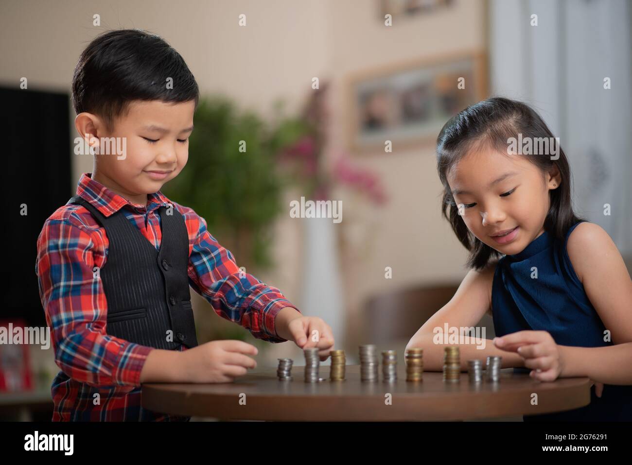 The cute Malaysian kids counting coins on a table Stock Photo - Alamy