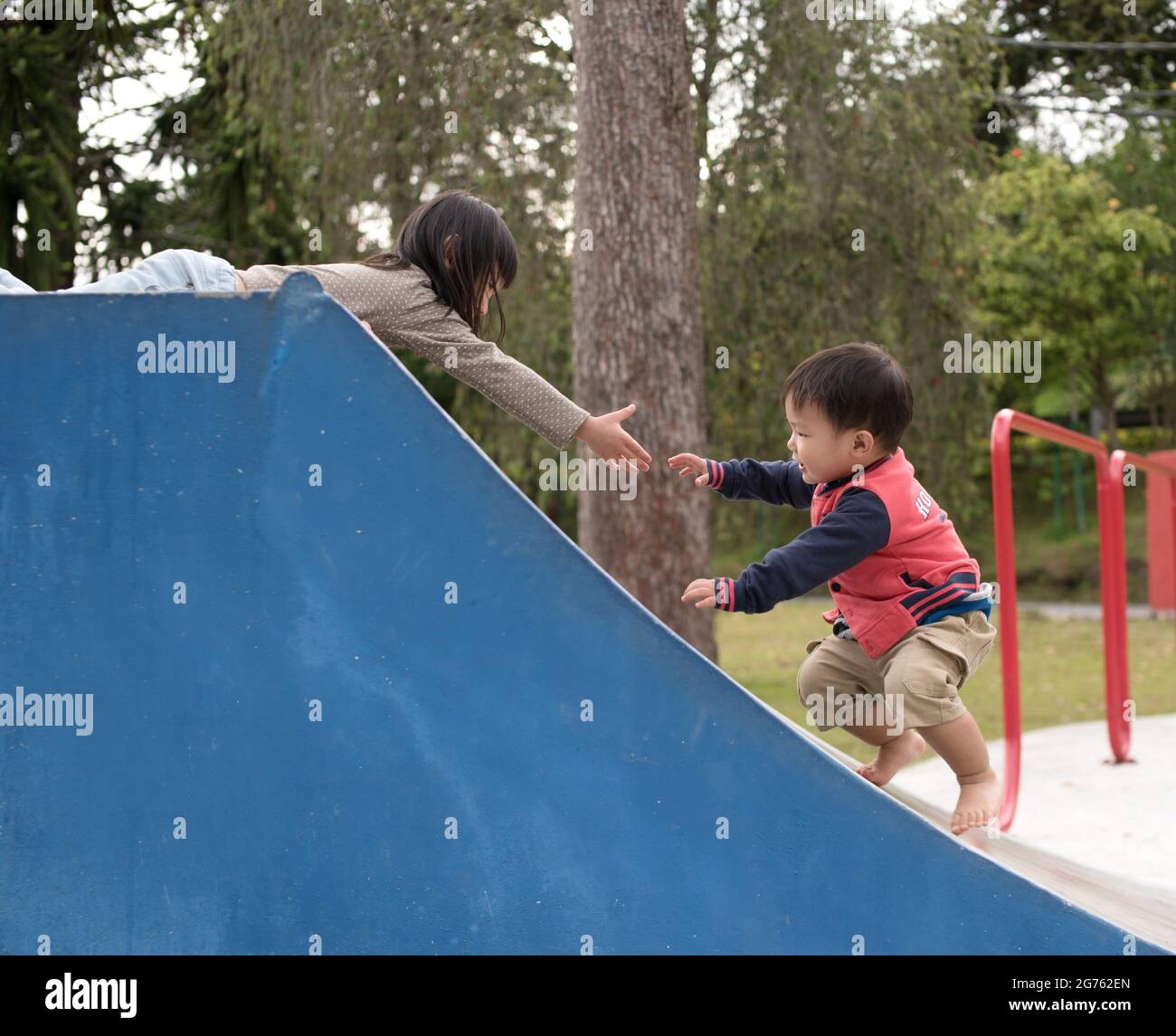 The older Malaysian child helping younger child up the ramp while ...