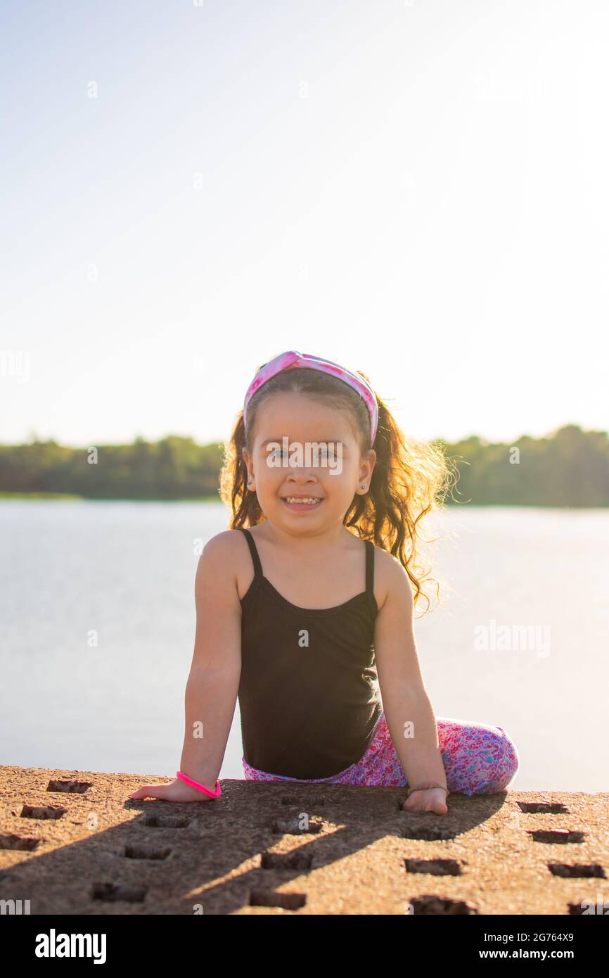 A cute Spanish girl happily standing on the riverside with the river on ...