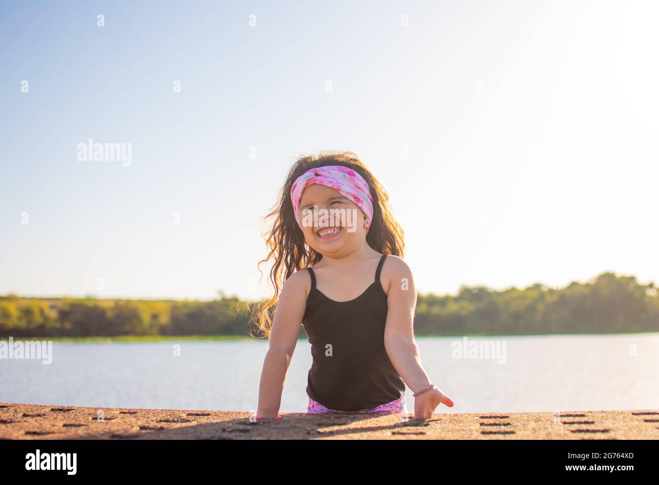 A cute Spanish girl happily standing on the riverside with the river on ...