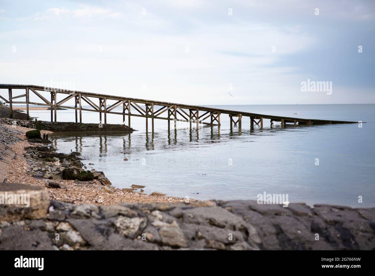 Sloping pier seascape with shingle and rock wall Stock Photo - Alamy