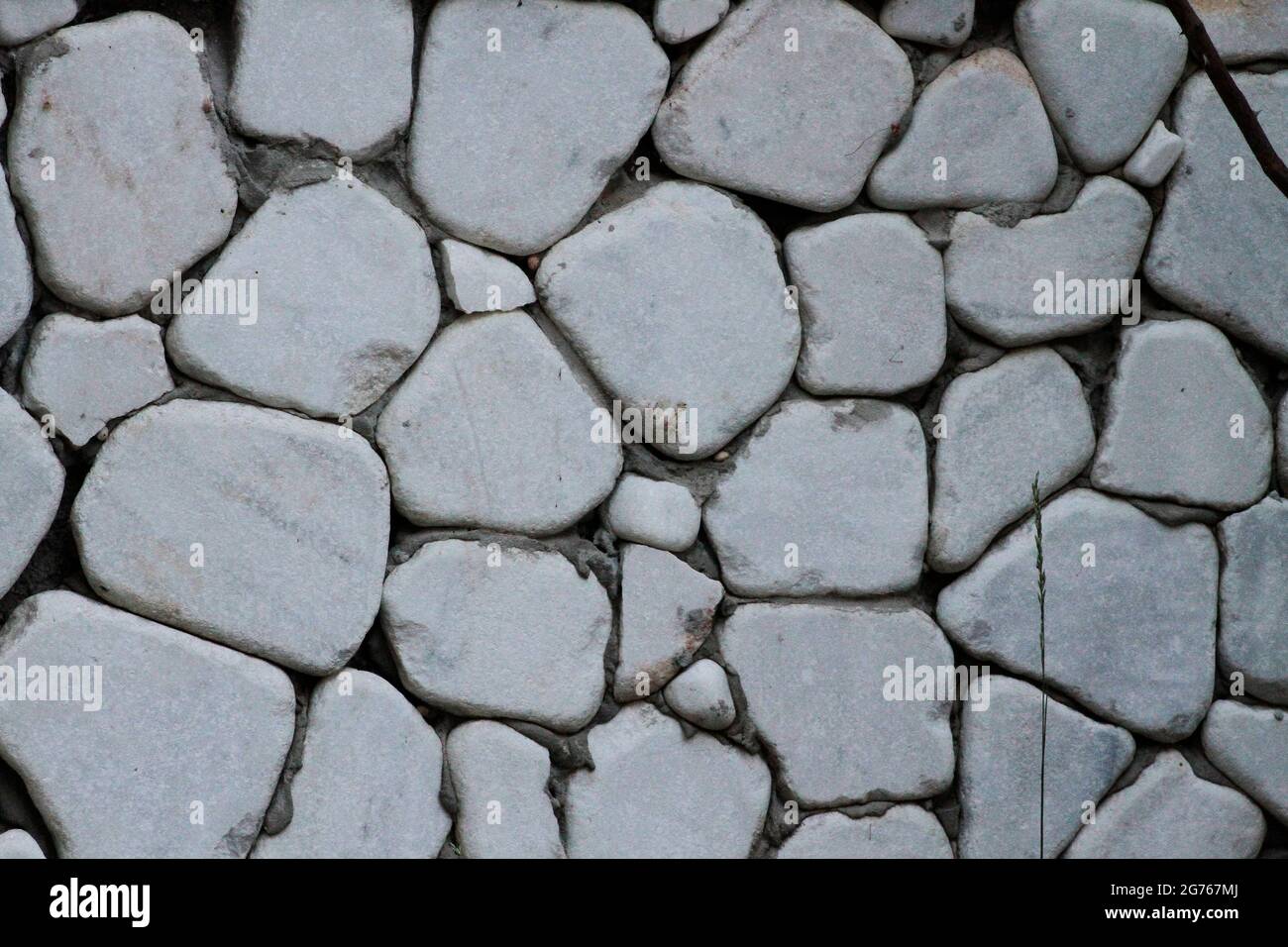 Wall cladding made using white, rounded white stones and grass. Wall ...