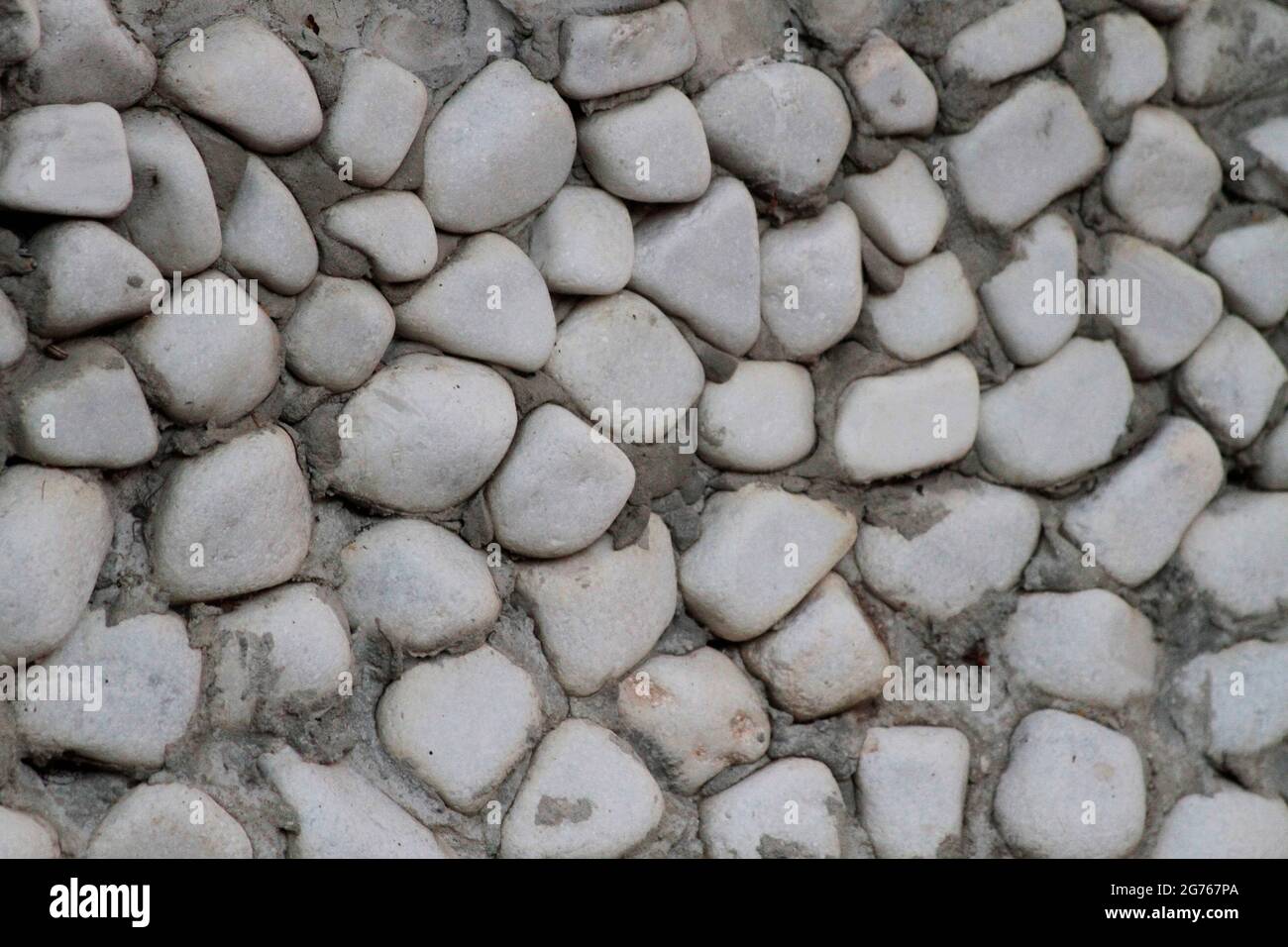 Wall cladding made using white, rounded white stones and grass. Wall ...