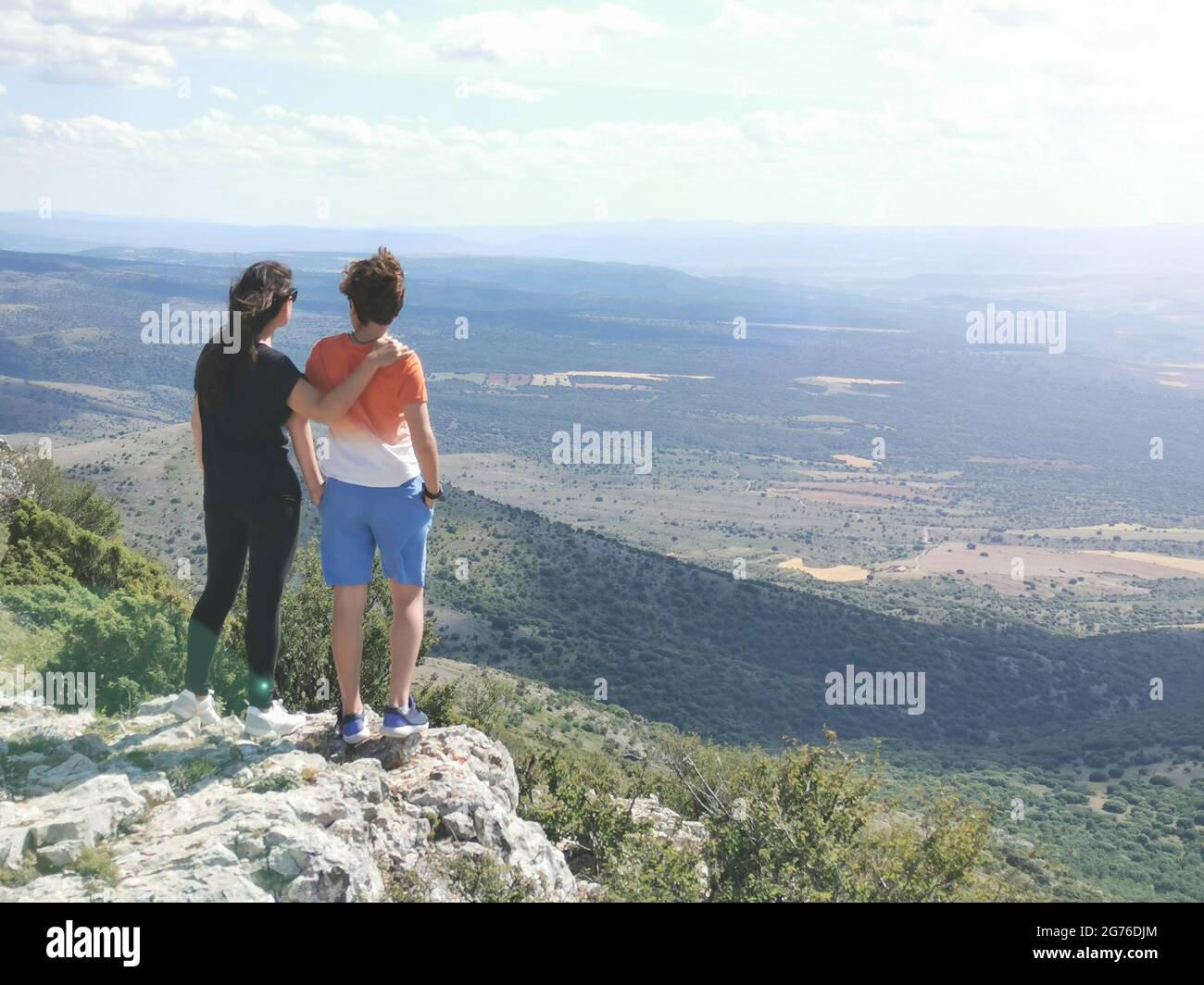 A beautiful couple standing on the edge of a hill and admiring the ...