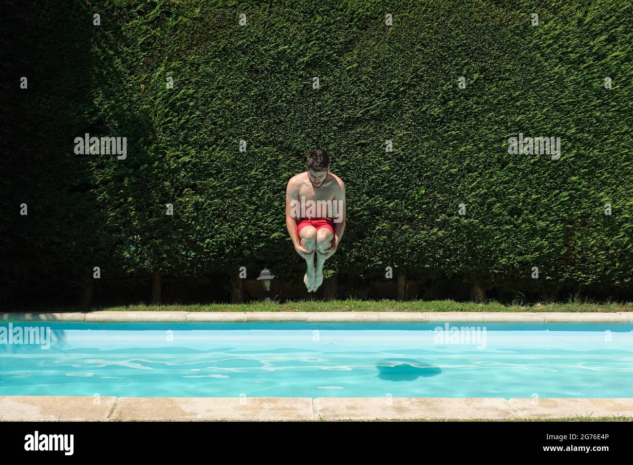 Young man cannonball jumping into a swimming pool. Summer concept Stock ...