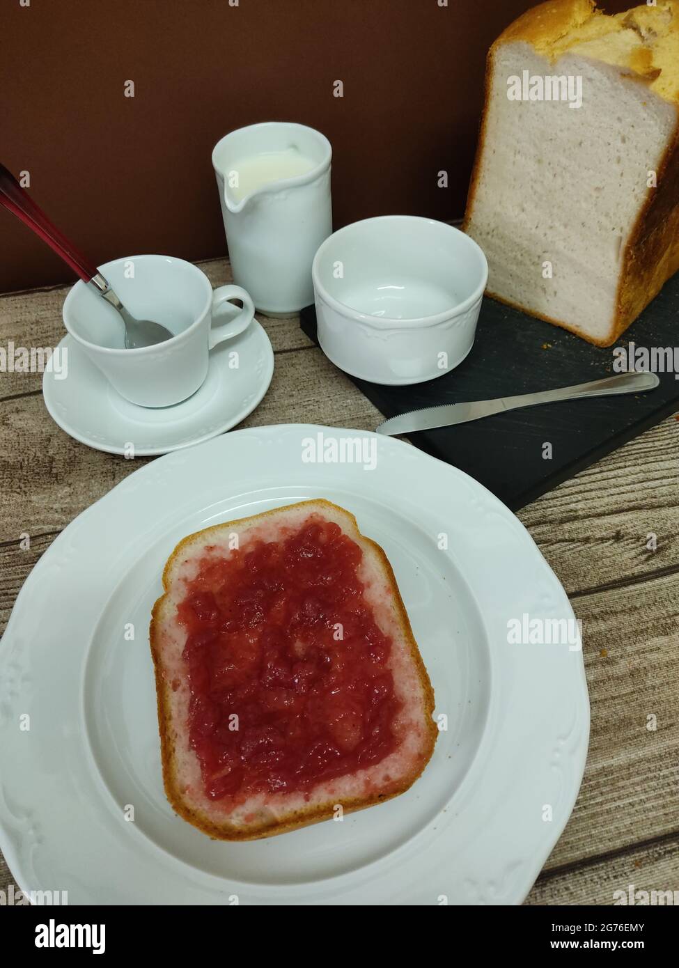 A closeup of tableware and a piece of bread with jam on the plate Stock ...