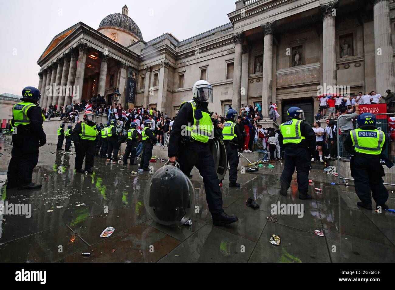 A police officer carries riot shields as colleagues observe England ...