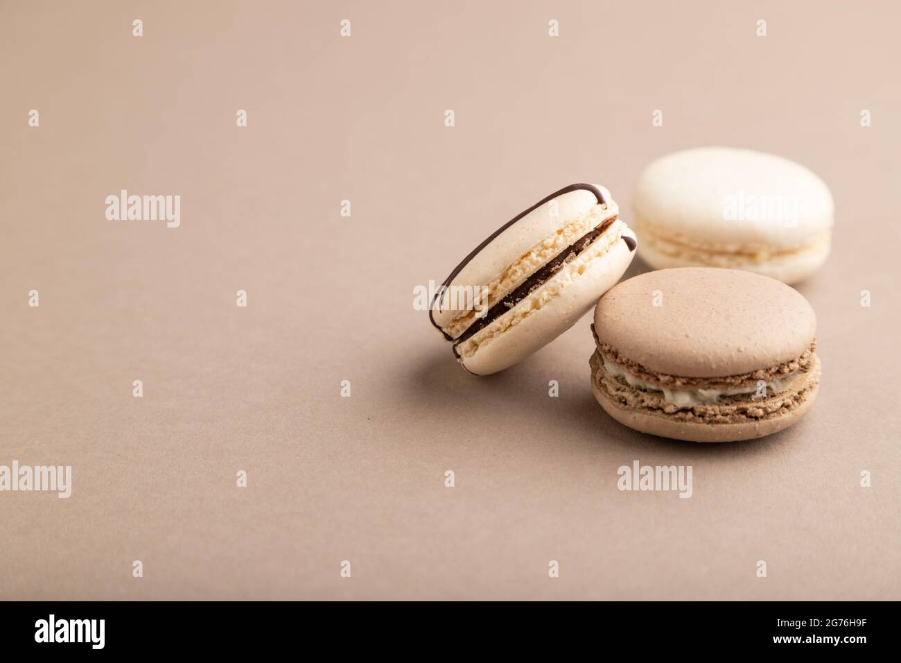 Brown and white macaroons on beige pastel background. side view, copy ...