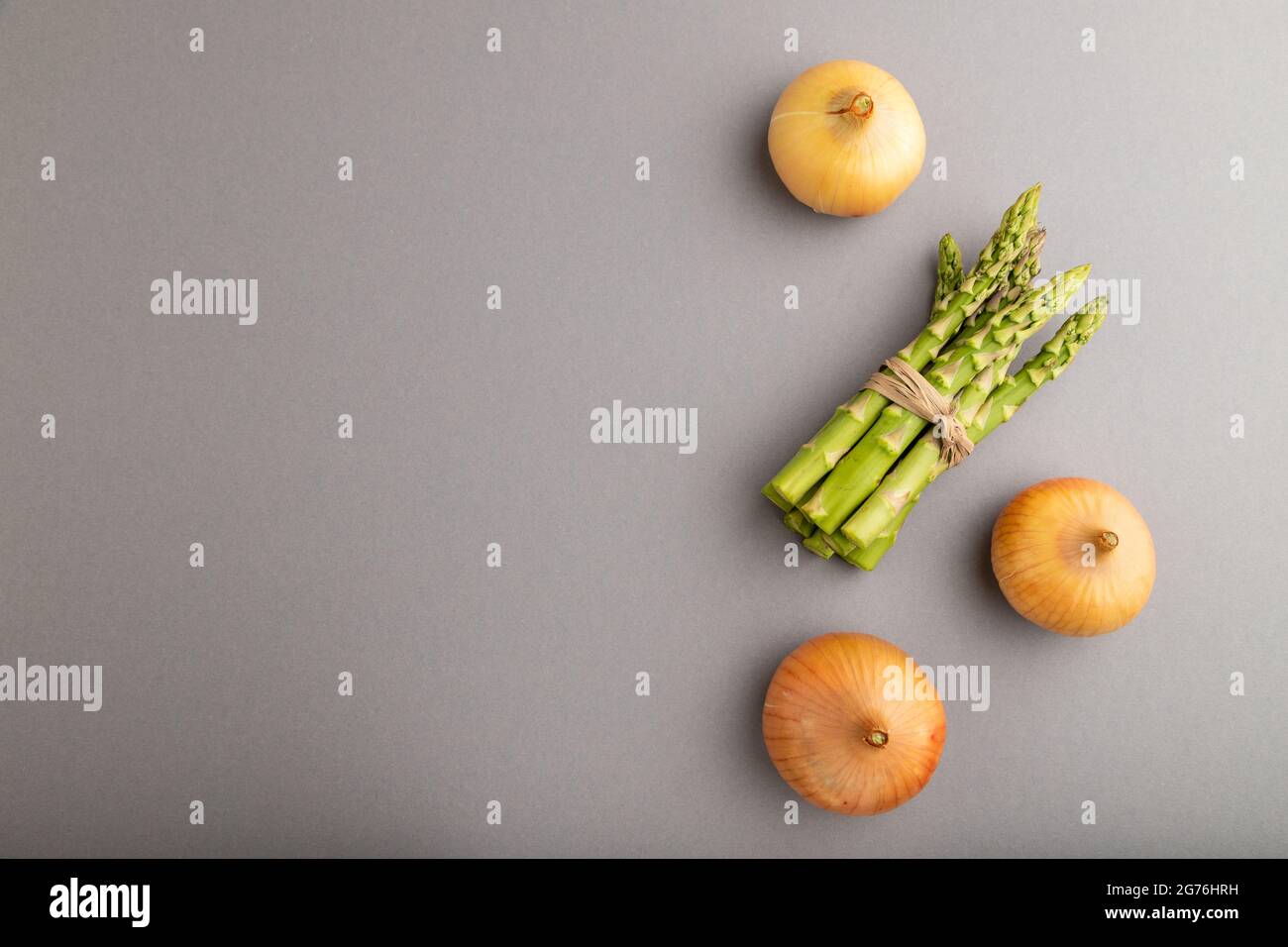 Bunch of fresh green asparagus and onion on gray pastel background. Top ...