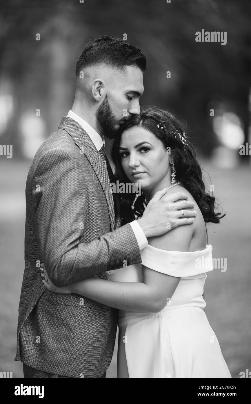 A beautiful newly-married couple posing in a park for the wedding ...