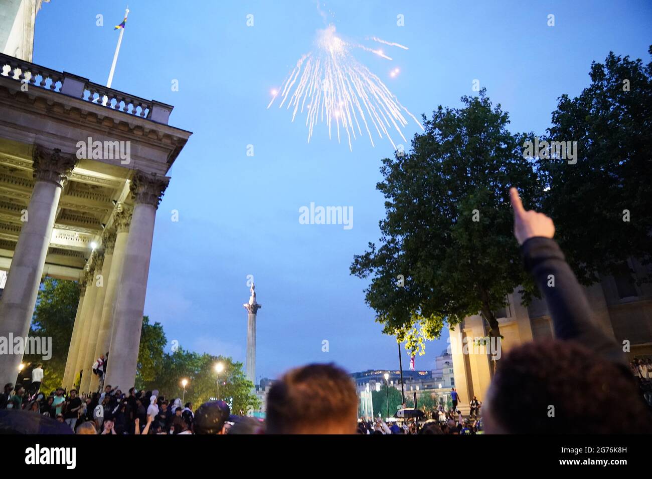 A fan points to a firework in the sky over London's Trafalgar Square ...