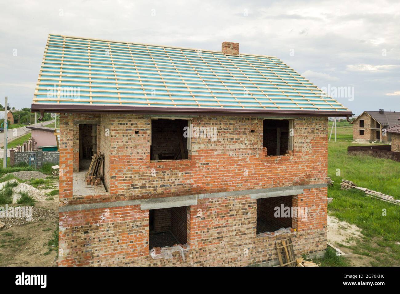 Aerial view of a brick house with wooden roof frame under construction ...