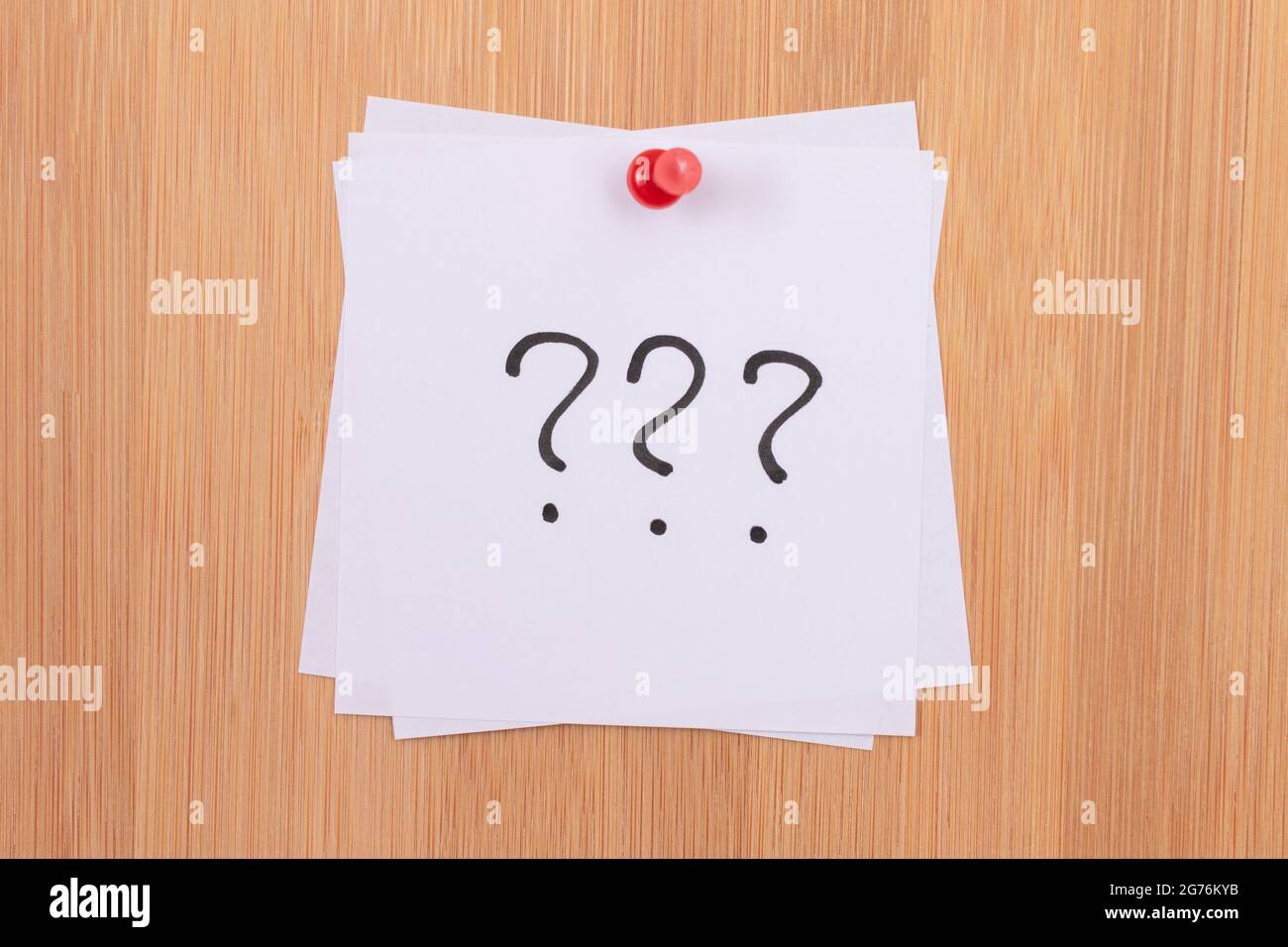 White Sticky Notes with Three Question Marks Pinned to the Wooden ...